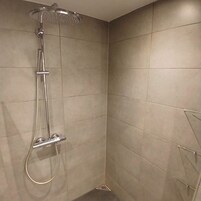 Chuveiro com chuveiro manual e painel de controle fixado na parede.