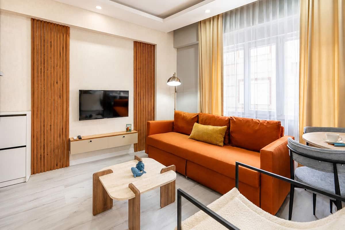 Uma sala de estar moderna com um sofá, uma mesa de centro, uma TV e um abajur.