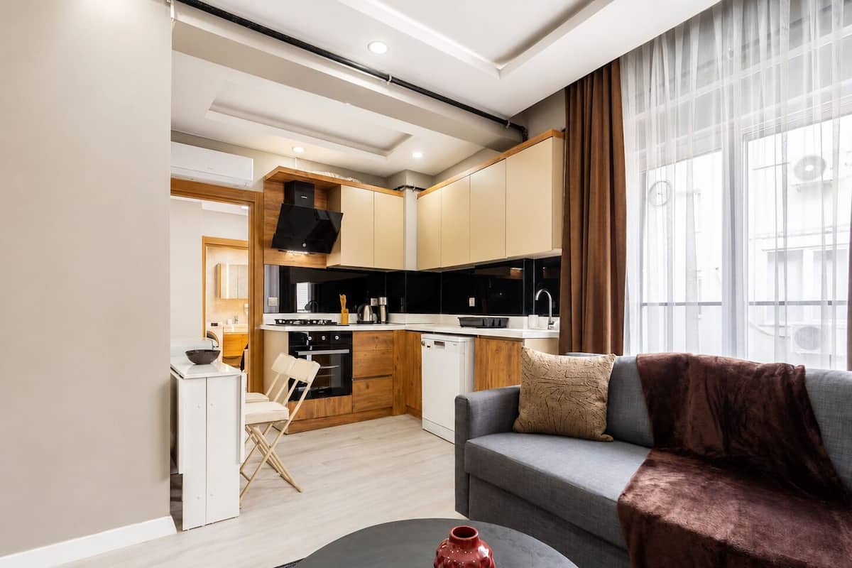 Uma sala de estar moderna com sofá, mesa de centro e cozinha ao fundo.