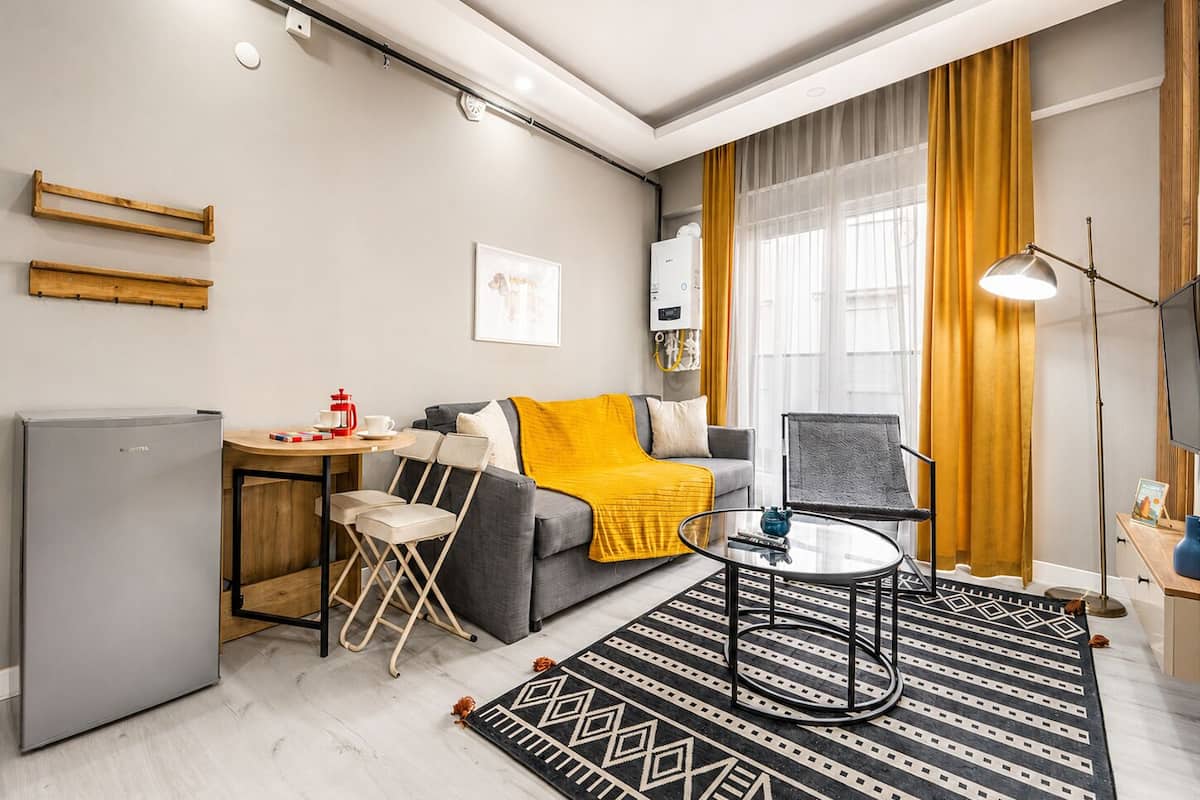 Uma sala moderna com sofá, mesa de centro e um pequeno espaço de refeições.