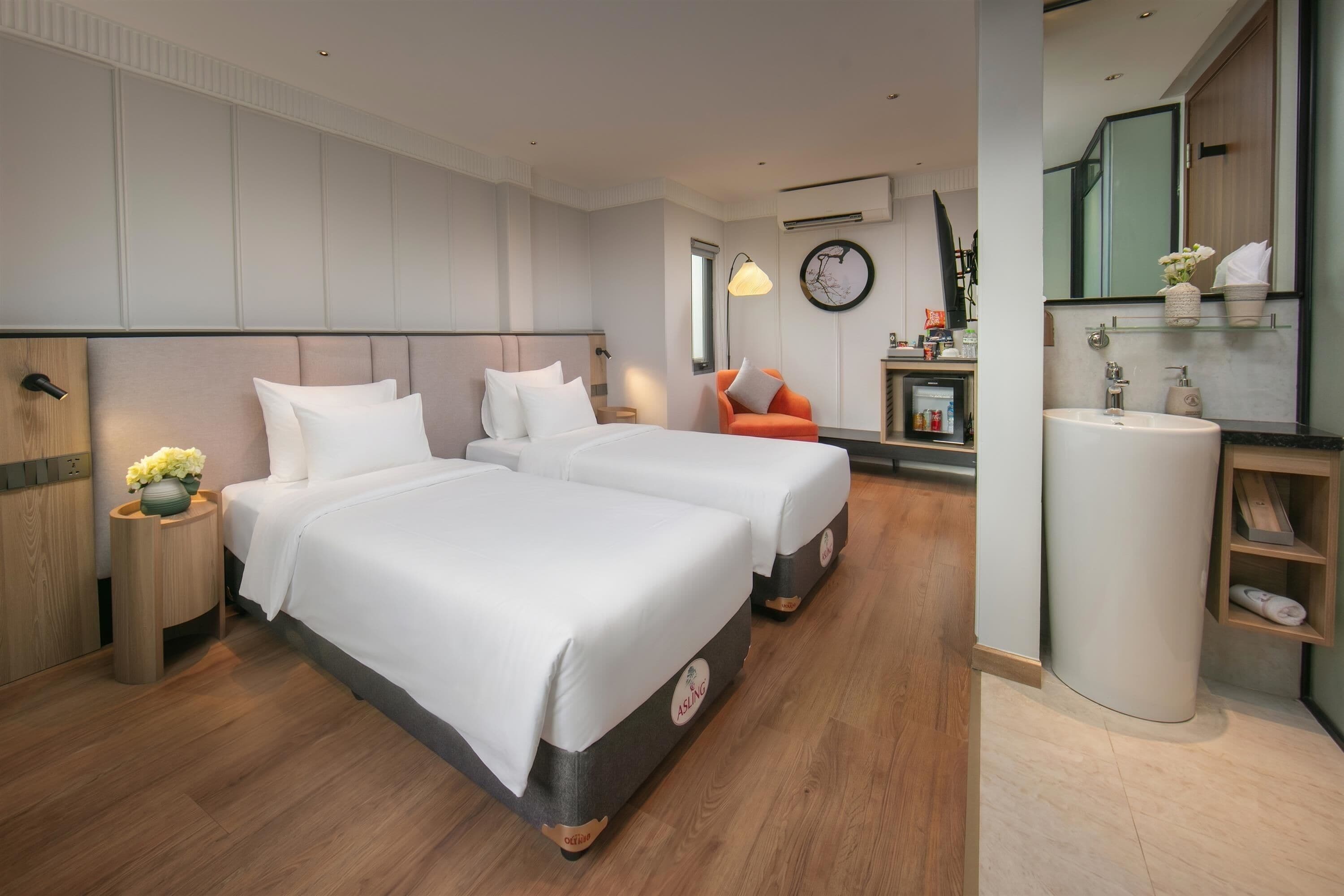 Quarto de hotel com duas camas, banheiro e uma pequena área de estar.