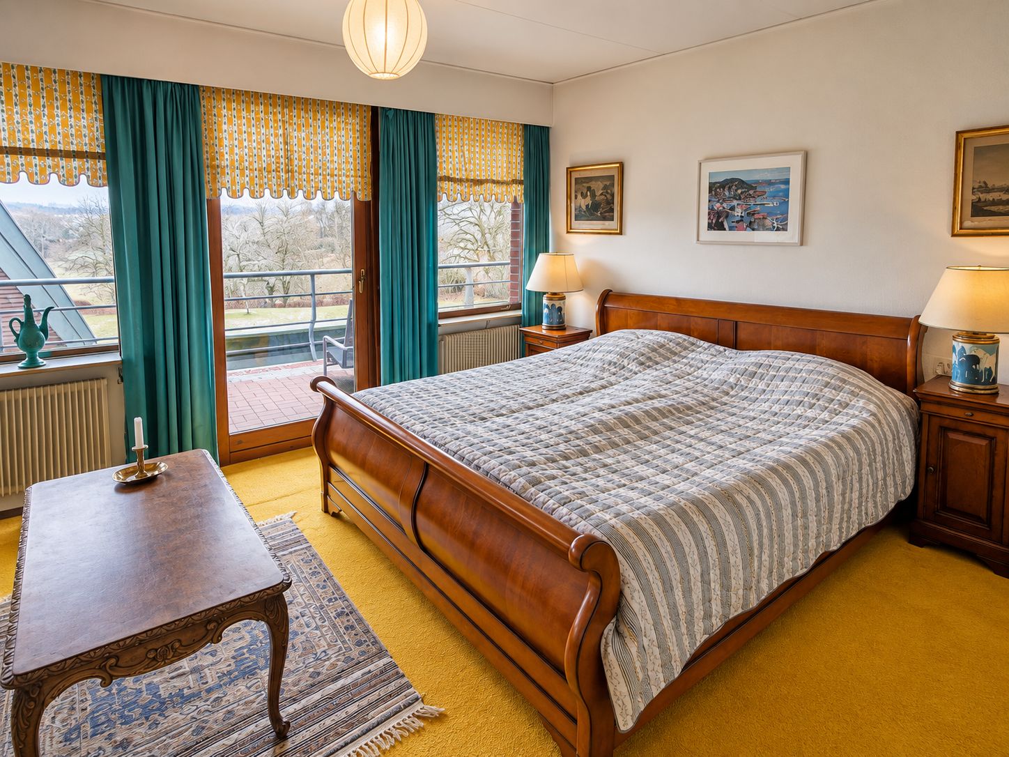Um quarto com uma cama de madeira, uma mesa de cabeceira, uma mesa e vista para o exterior pela janela.
