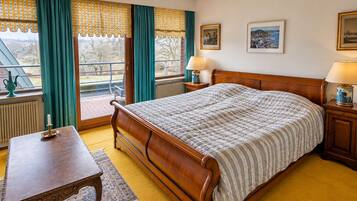Um quarto com uma cama de madeira, uma mesa de cabeceira, uma mesa e vista para o exterior pela janela.