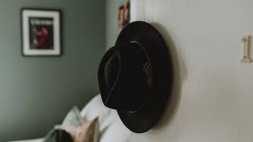 Quarto com uma cama, um chapéu fixado na parede e um quadro emoldurado.