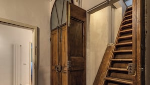 Escada de madeira com corrimão de metal e porta de madeira com trinco metálico.