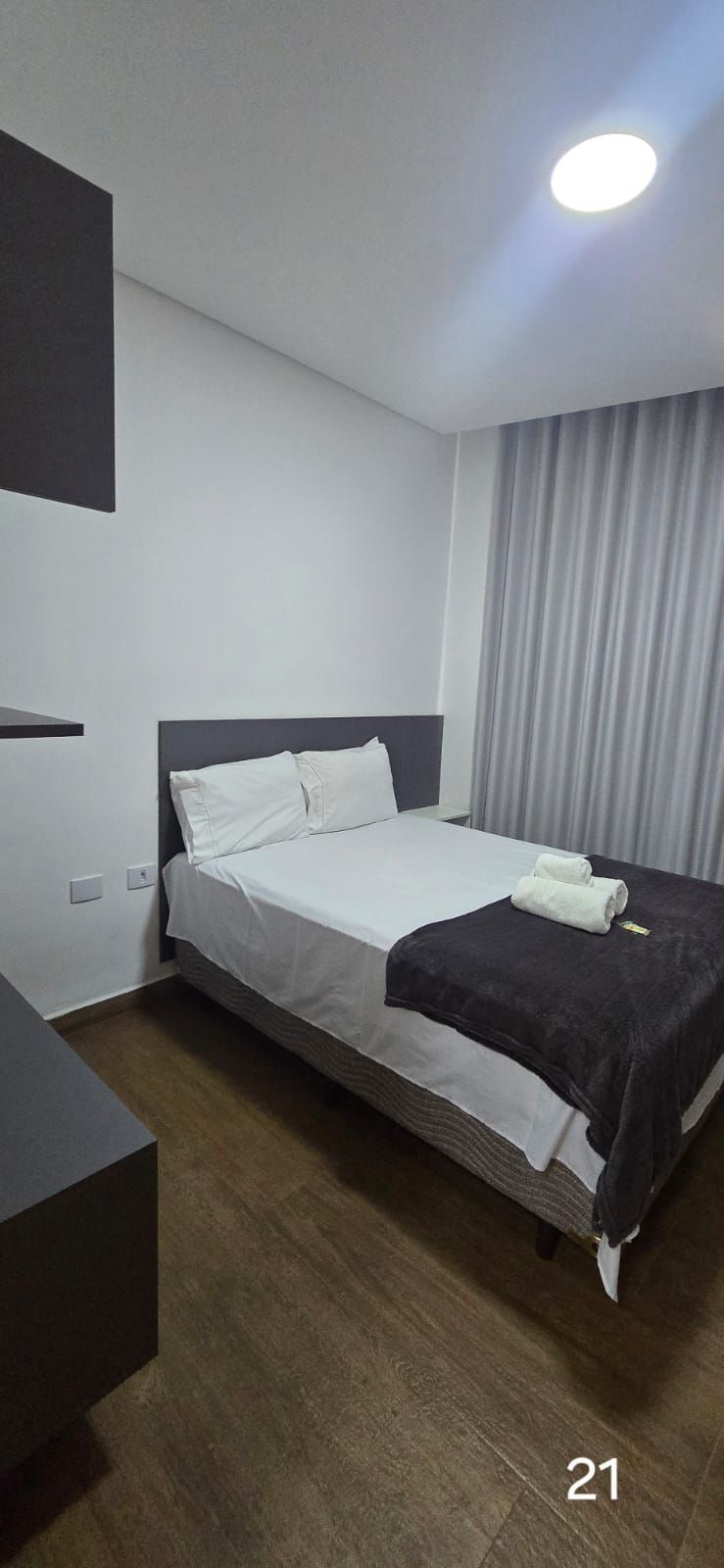 Quarto de hotel com cama, escrivaninha e cortina.