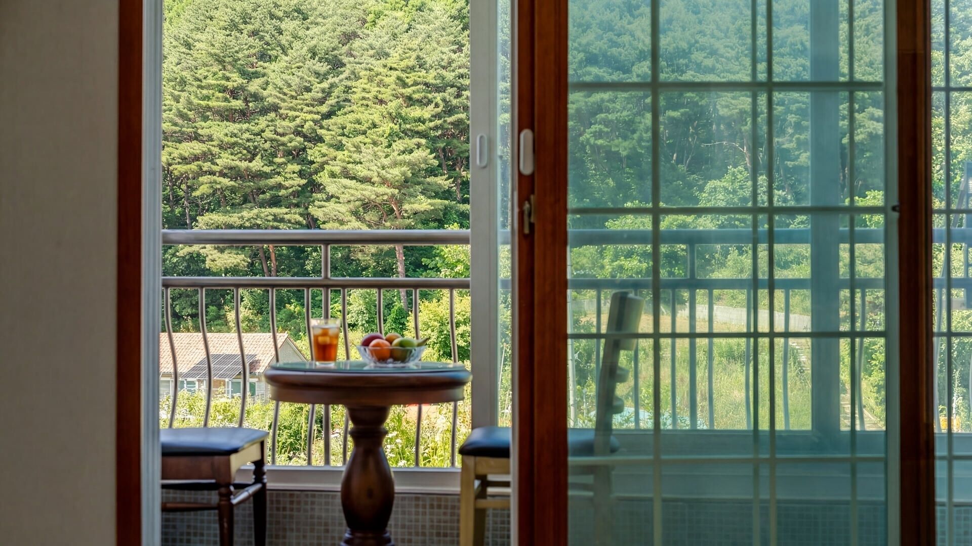Uma varanda com mesa, cadeiras e vista para uma área arborizada.