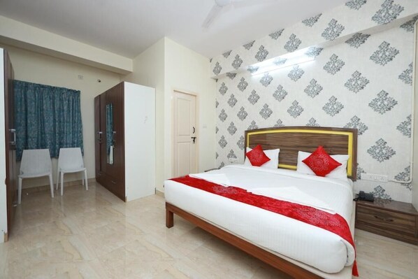 Quarto de hotel com cama, guarda-roupa, secretária e cadeiras.