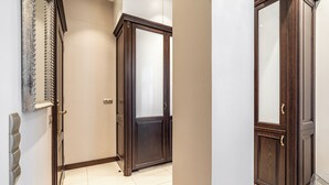 Um corredor com um guarda-roupa de madeira, um espelho e um interruptor de luz.