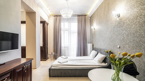 Quarto de hotel moderno com uma cama grande, televisão, área de refeições e um vaso de flores.