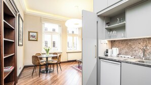Uma cozinha moderna com máquina de lavar louça embutida, sala de jantar com mesa redonda e cadeiras, e vista da cidade através de amplas janelas.