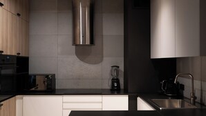 Uma cozinha moderna com um exaustor de aço inoxidável, um liquidificador embutido e uma cafeteira.