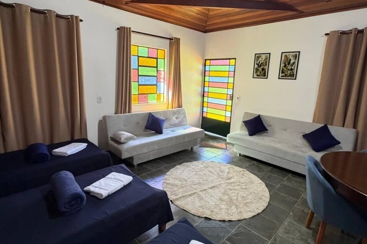 Quarto com duas camas, um sofá, um tapete redondo e uma mesa de jantar.