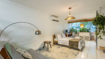 Quarto moderno com cama, mesa de cabeceira e escrivaninha. Há uma janela com vista para o exterior.