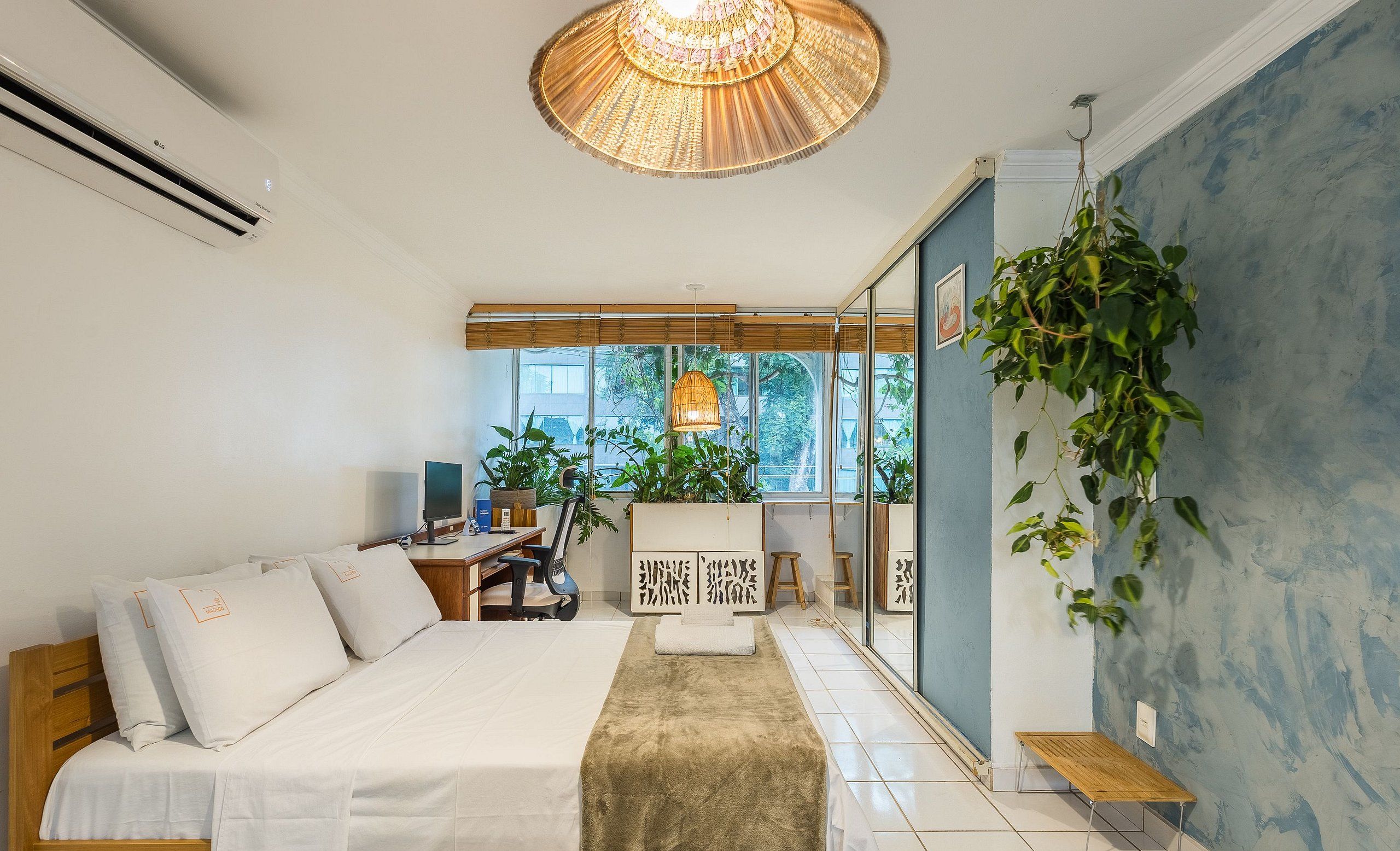 Quarto de hotel moderno com cama, escrivaninha e uma grande janela.