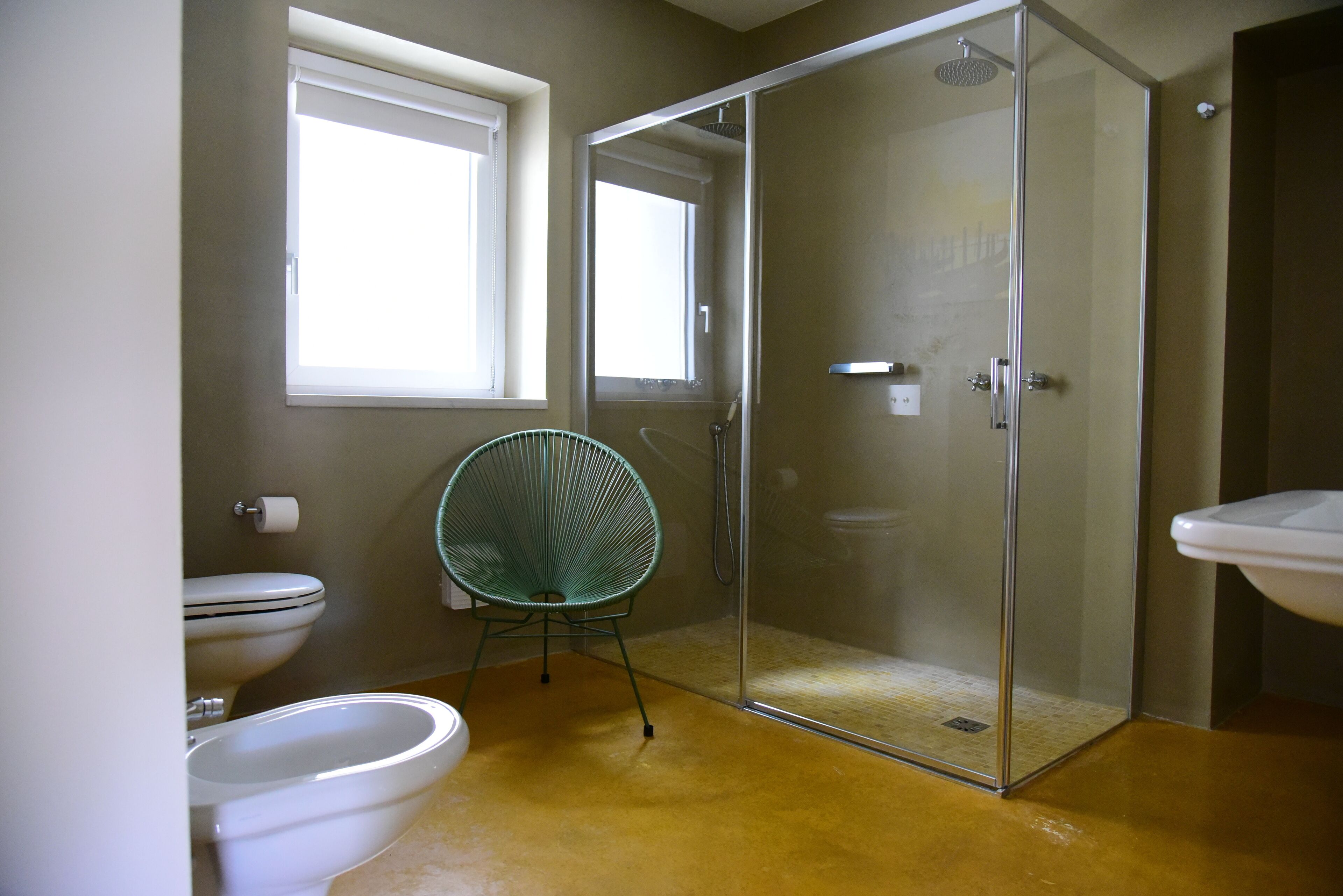 Casa de banho com sanita, bidé e cabine de duche envidraçada.