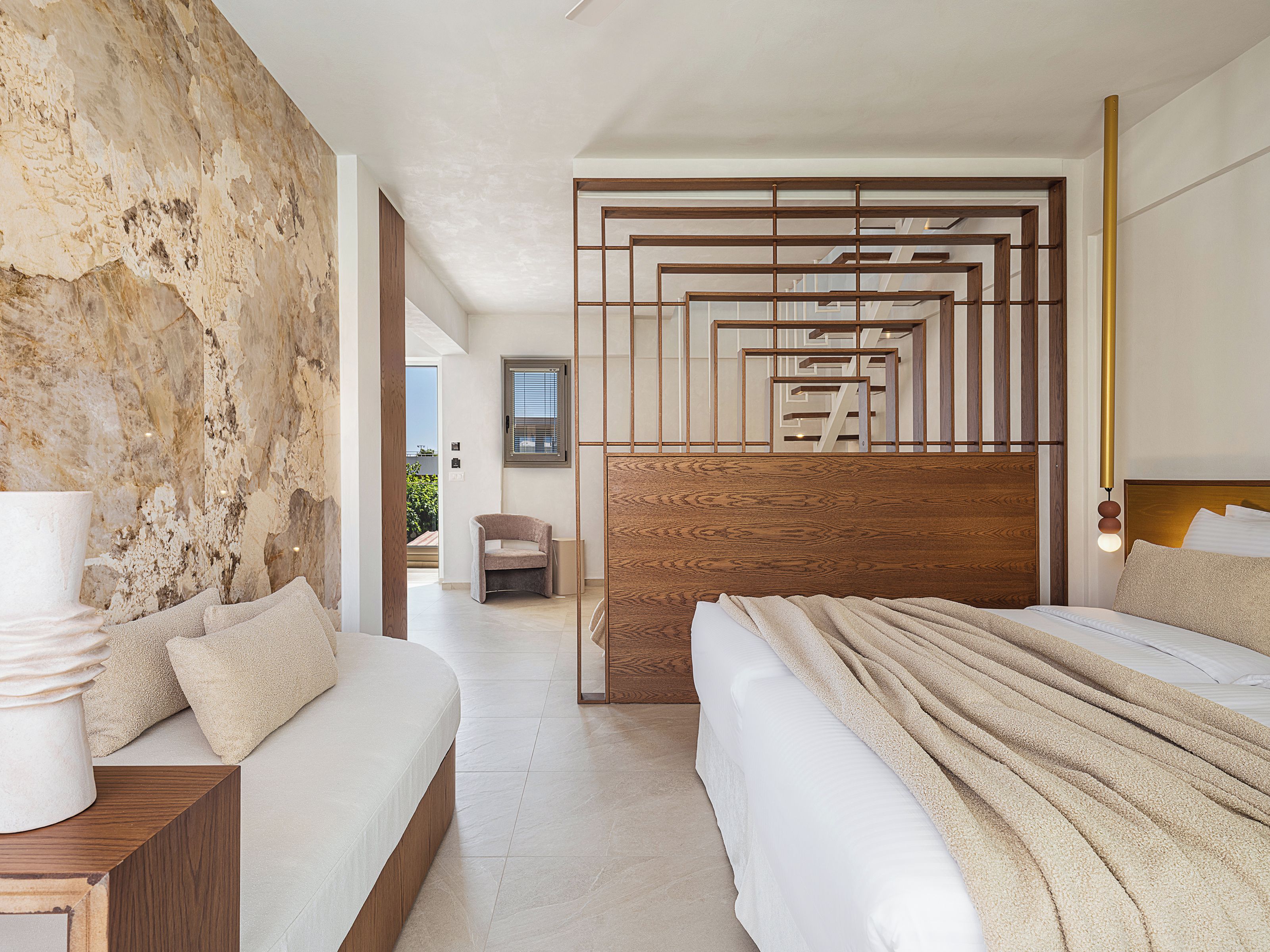 Quarto moderno com cama grande, sofá e divisória de madeira singular.