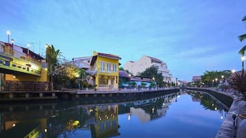 Um canal com edifícios refletidos na água, uma ponte e postes de luz.