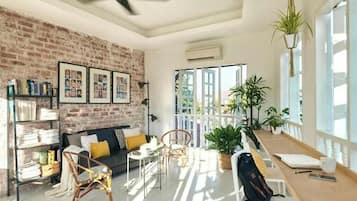 Uma sala de estar luminosa com parede de tijolos, um sofá, uma mesa de centro e uma estante.