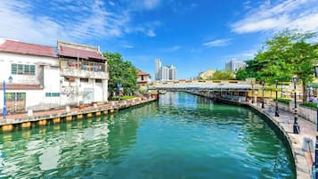 Um canal com edifícios em ambos os lados, uma ponte ao fundo e céu claro.