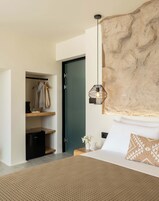 Quarto com cama, mesa de cabeceira, luminária pendente, guarda-roupa e uma porta.