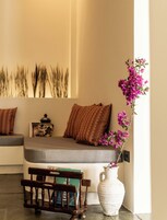 Uma área de estar acolhedora com um banco, almofadas e um vaso de flores.
