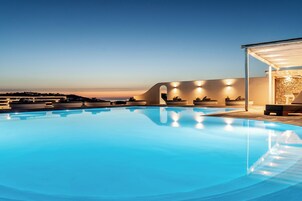Piscina com vista clara do horizonte, área de estar coberta e parede de pedra.