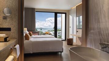 Quarto de hotel moderno com uma cama grande, uma banheira, uma TV e vista para o mar.