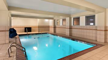 Uma grande piscina interior com marcações claras nas pistas de natação, um trampolim e chão revestido de azulejos.
