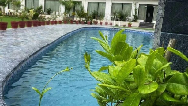 Piscina com um edifício moderno ao fundo.