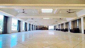 Um amplo hall de hotel com teto alto, grandes janelas e chão de azulejos.