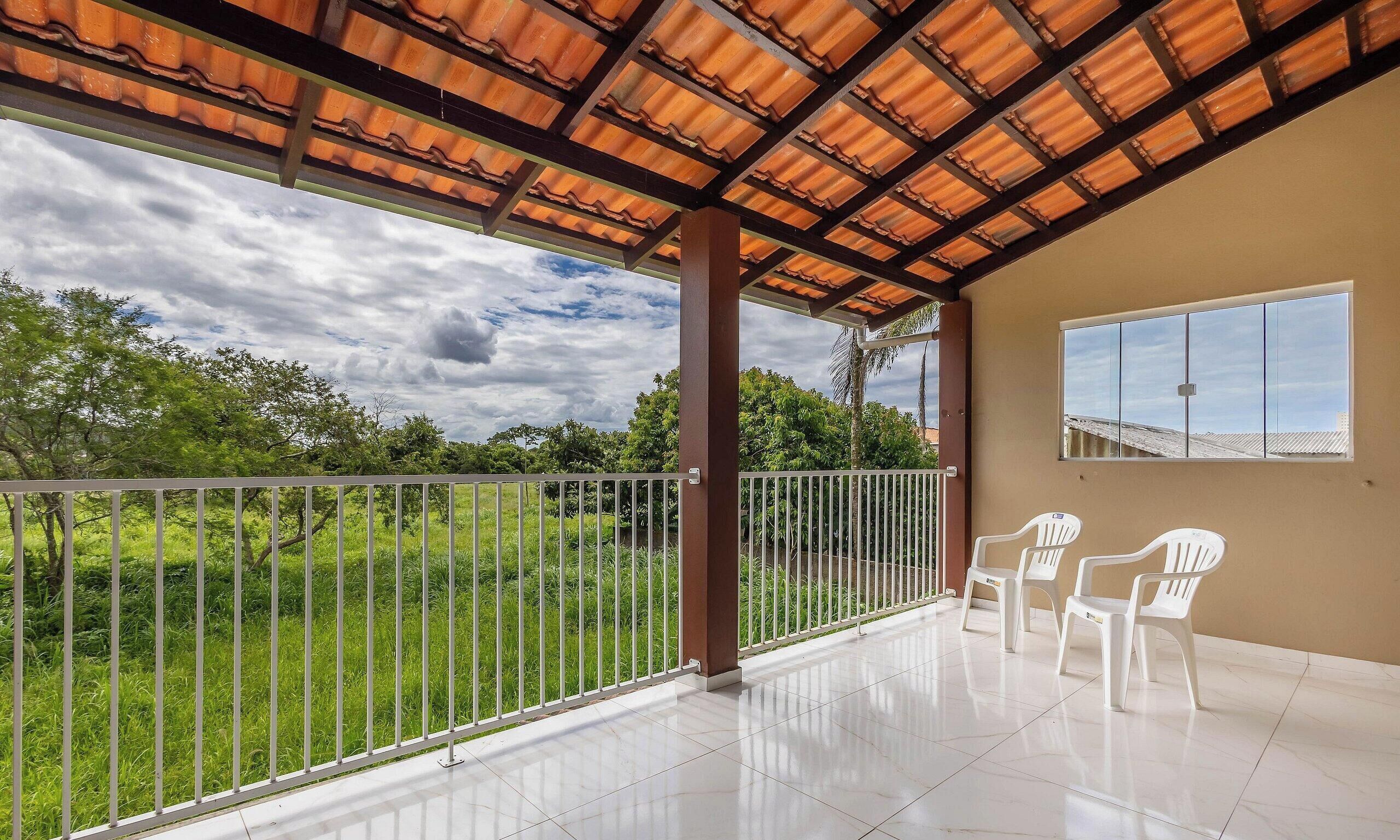 Varanda coberta com vista para vegetação e um céu nublado.