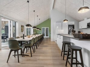Cozinha moderna com ilha central, banquetas e iluminação pendente.