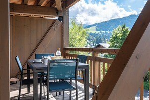 Um deck de madeira com mesa e cadeiras, com vista para uma paisagem montanhosa.