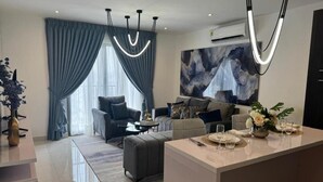 Uma sala de estar moderna com um sofá, uma mesa de centro e uma área de jantar com uma mesa posta para dois.