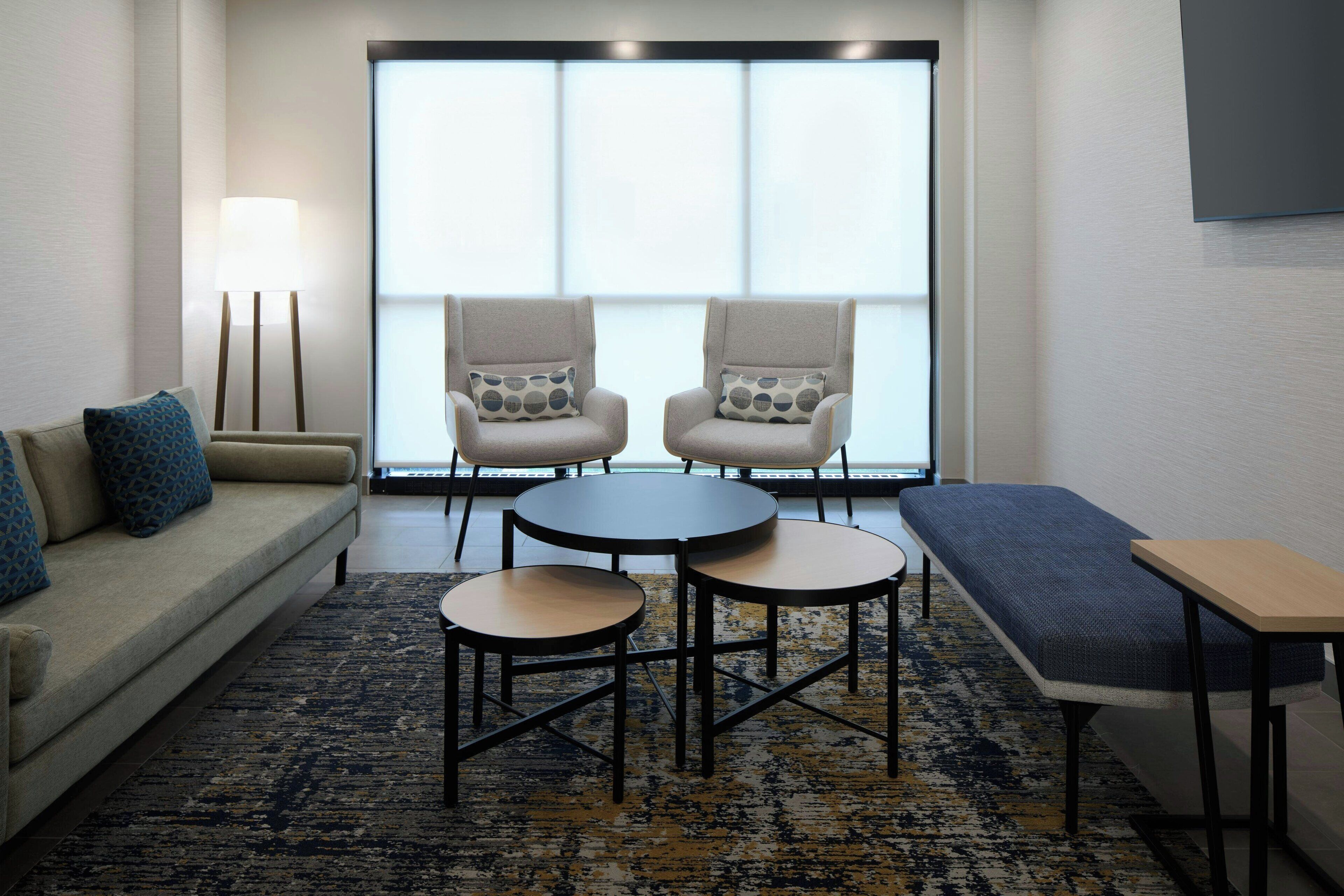 Uma sala de estar moderna com um sofá, duas poltronas, uma mesa de centro e um banco.