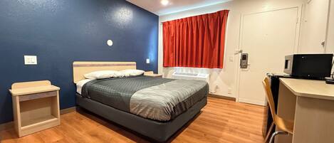 Um quarto com cama, mesas de cabeceira, escrivaninha e uma cadeira.