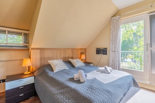 Quarto com uma cama grande, uma mesa de cabeceira, um abajur e vista para o exterior pela janela.
