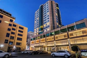 Edifício de vários andares com design arquitetônico moderno, destacando-se por um elemento vertical imponente e uma série de varandas.