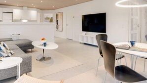 Uma sala de estar moderna com um sofá, uma mesa de jantar e uma televisão.