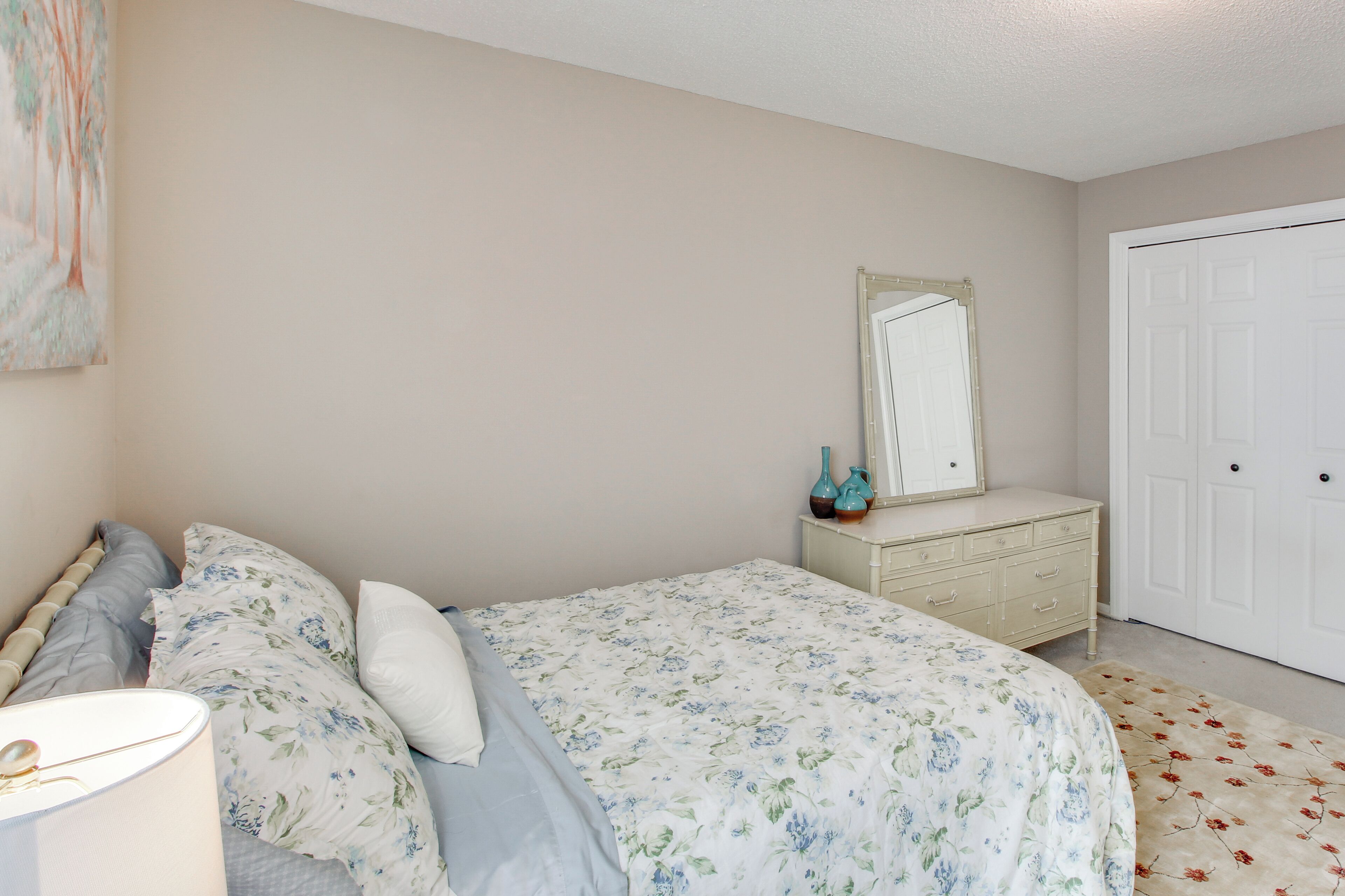 Quarto com cama, penteadeira, espelho e porta.