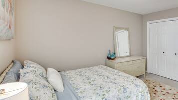 Quarto com cama, penteadeira, espelho e porta.