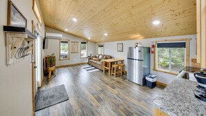 Cozinha espaçosa com piso de madeira, área de jantar e sala de estar com sofá e máquina de café.