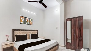 Quarto com cama, mesa de cabeceira, espelho e ventoinha no teto.