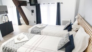 Quarto de hotel com duas camas, uma escrivaninha, uma cadeira, uma televisão e uma janela com cortinas.