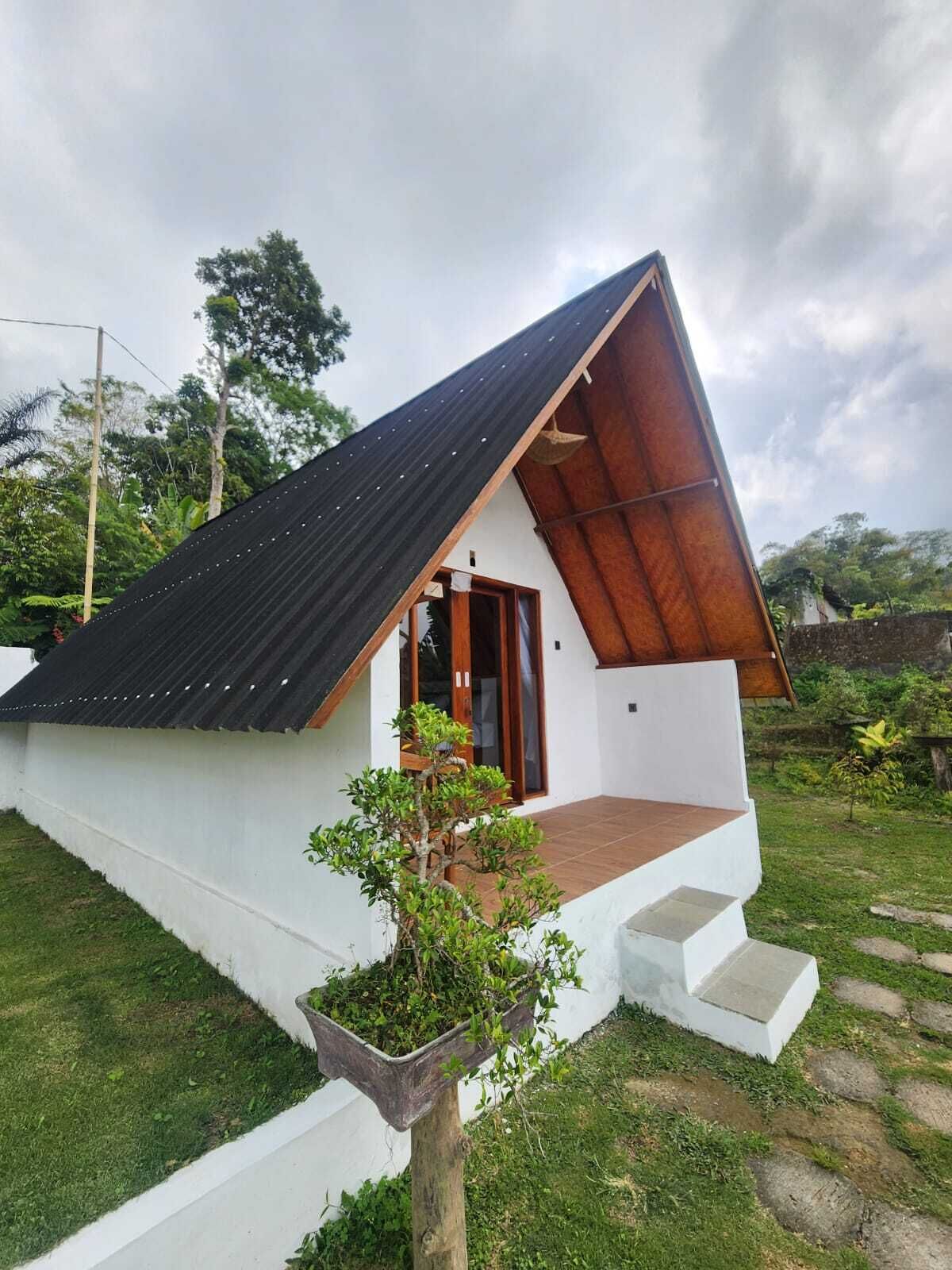 Uma casa moderna com telhado inclinado, porta de madeira e um pequeno alpendre.