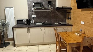 Uma cozinha compacta com micro-ondas, cafeteira e televisão na parede.