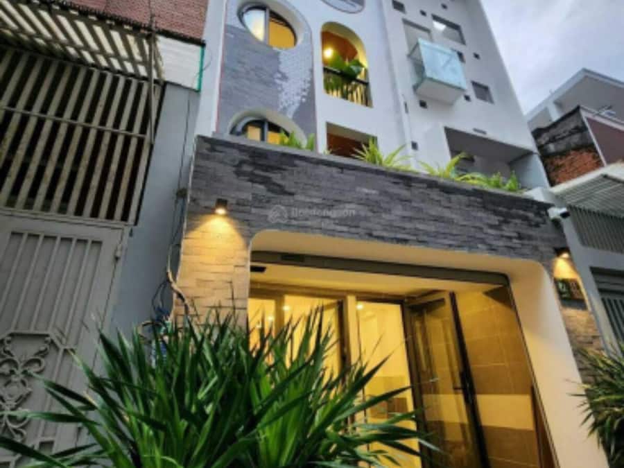 Um edifício moderno com telhado plano, janelas amplas e uma varanda com plantas.