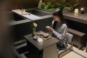 Uma sala de jantar moderna e minimalista com uma mesa de madeira, um vaso com flores brancas e um tabuleiro com pratos.