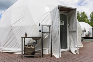 Uma tenda branca com uma porta, uma pia e um aquecedor portátil.